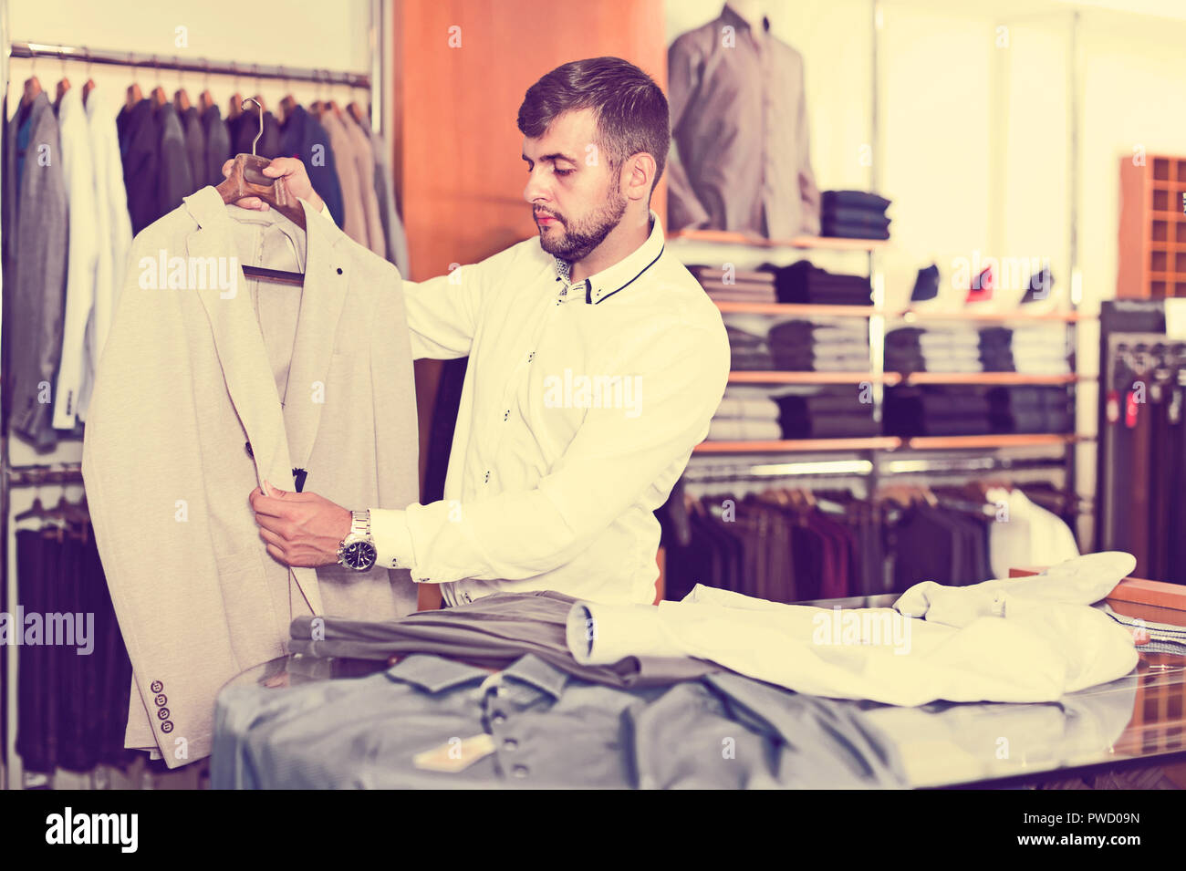 Smiling salesman demonstration classic jacket in men boutique Stock ...