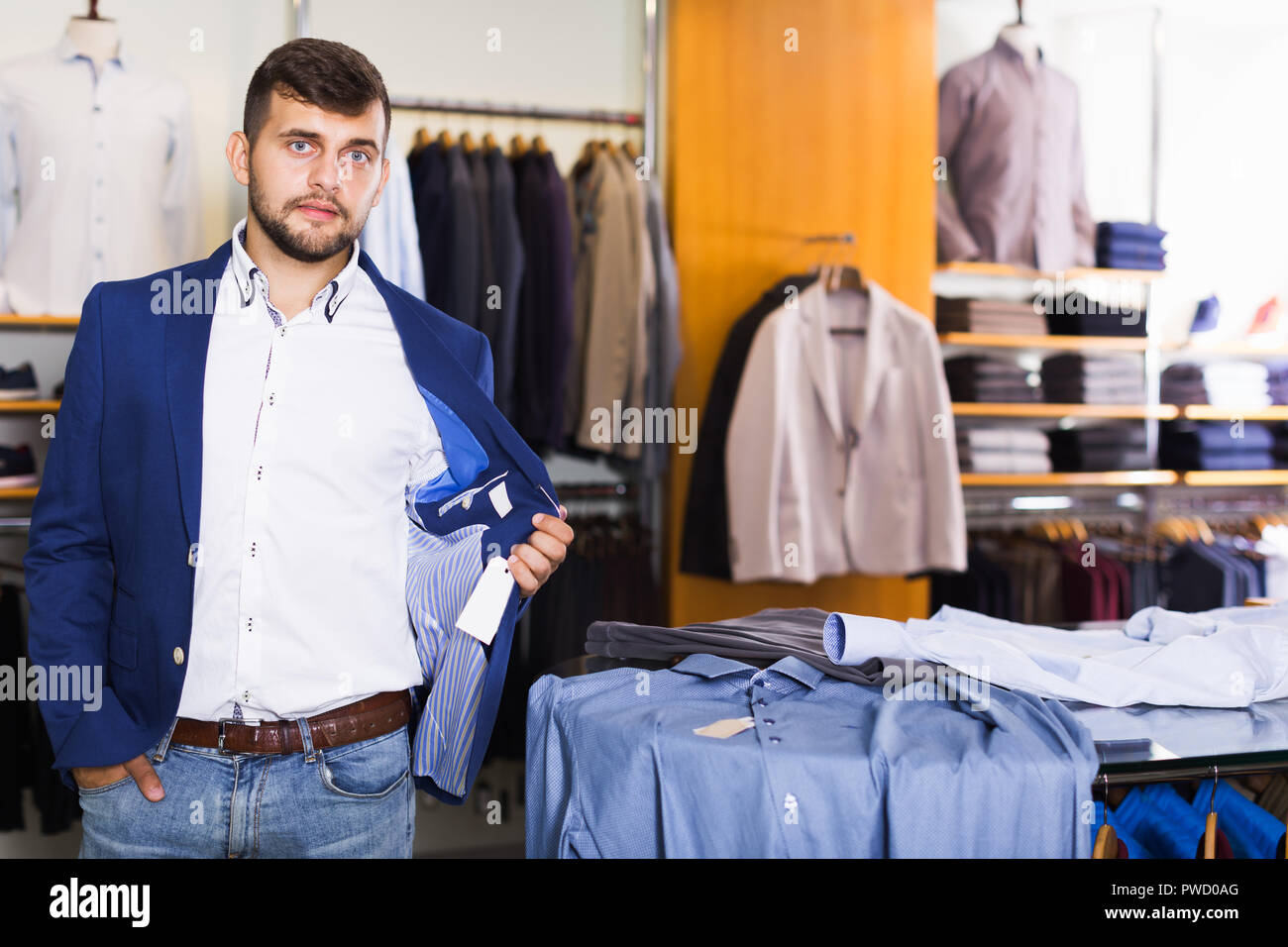 Happy man customer choosing jacket in men clothes shop Stock Photo - Alamy