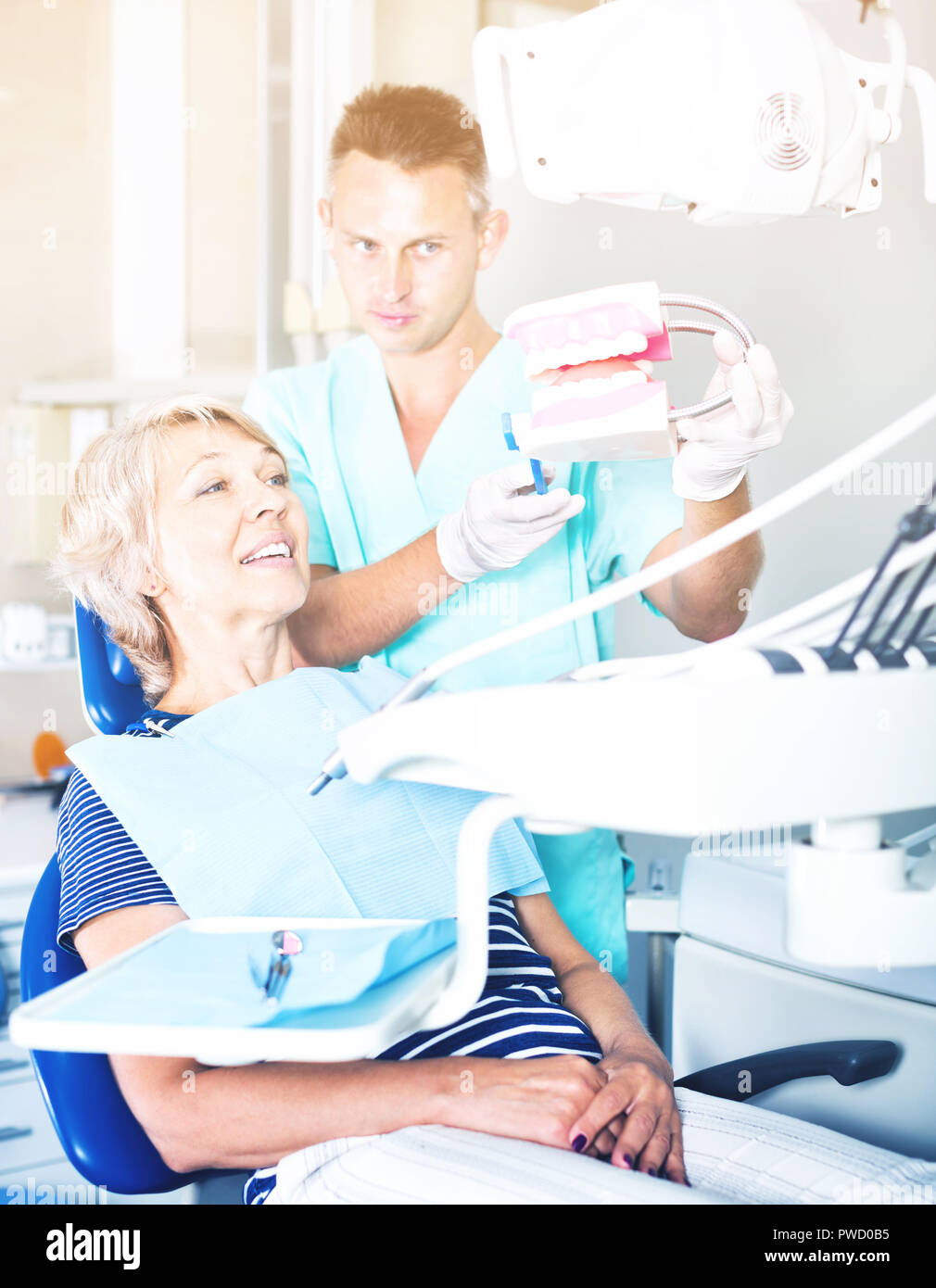 Professional dentist explaining to his female patient correct tooth ...