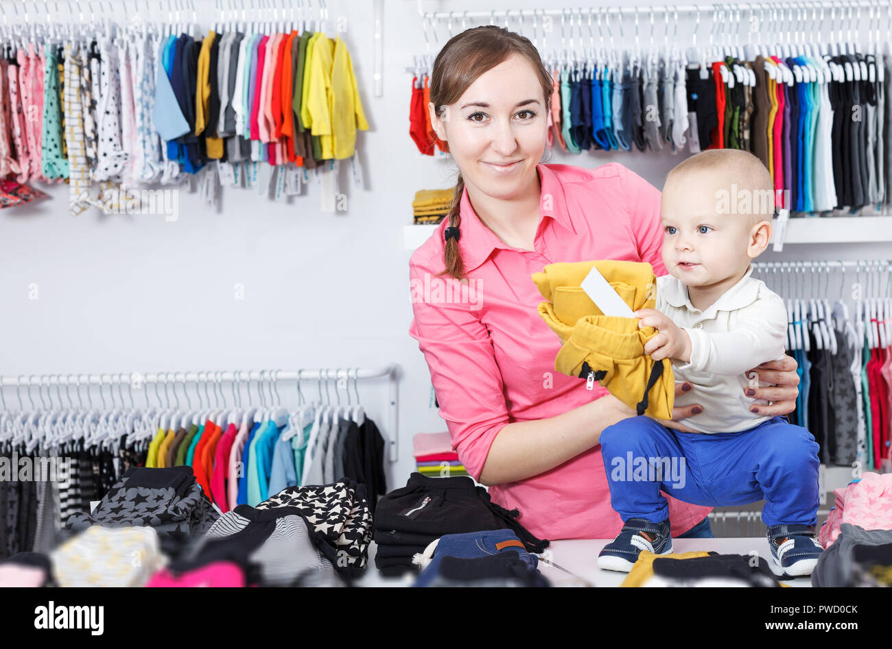 Portrait of smiling little kid who is posing when his mother choosing ...