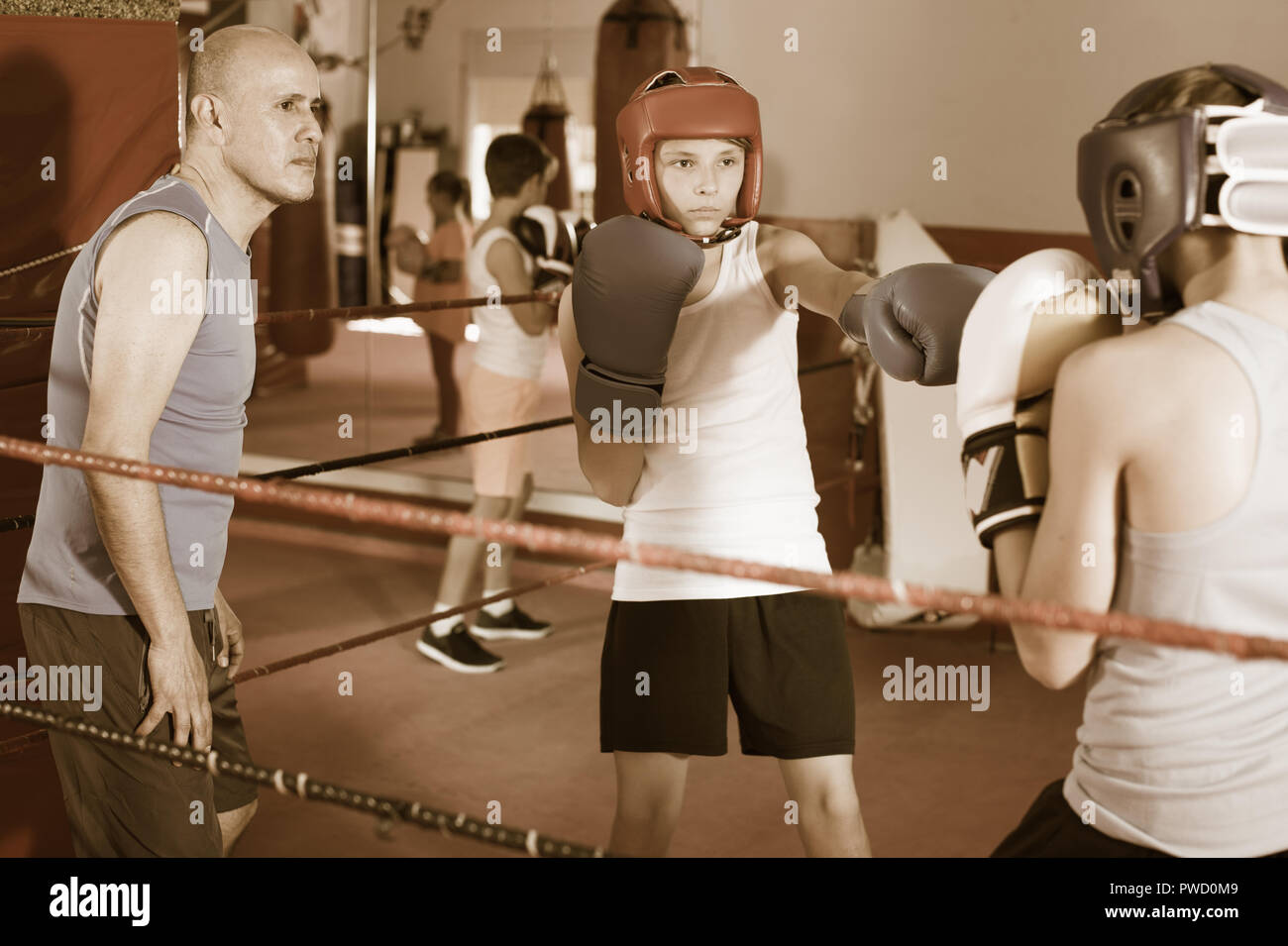 Teenage boy sportsman at boxing training with coach on boxing ring ...