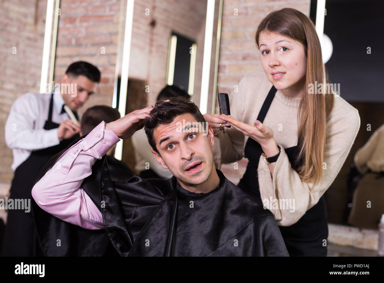 Man unpleasantly surprised by haircut from young woman hairdresser ...