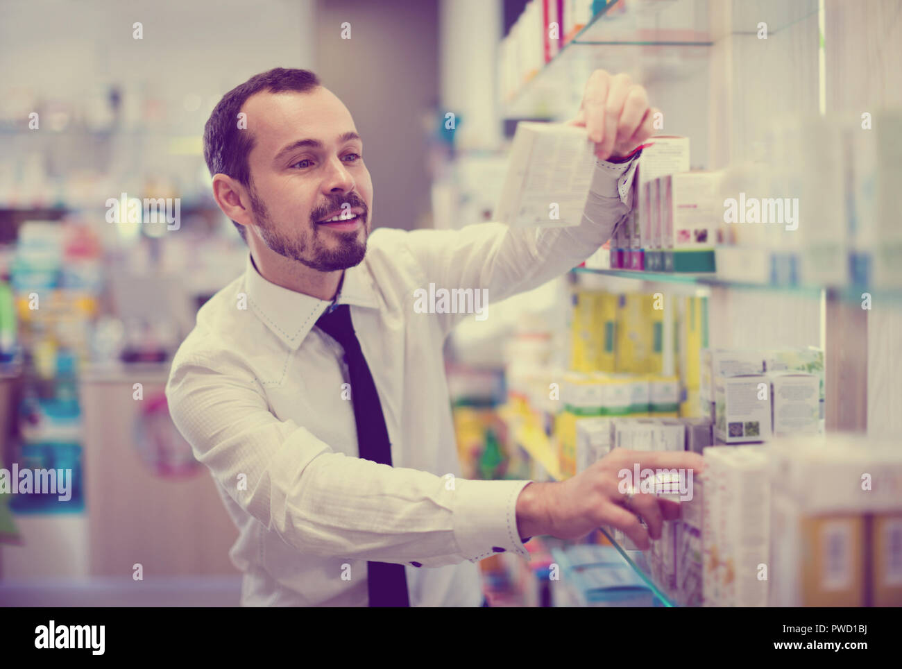 Smiling glad male customer looking for right medicine in pharmacy Stock ...