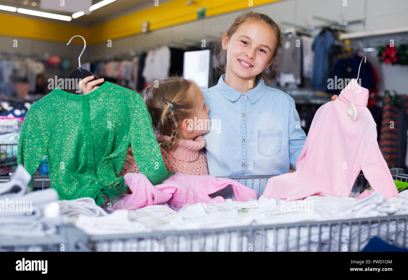 Portrait of two happy little girls with new clothes in shopping mall ...
