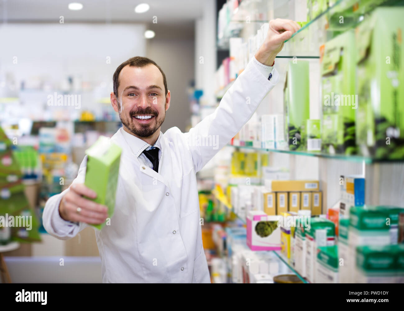 Smiling man pharmacist offering right drug in drugstore Stock Photo - Alamy