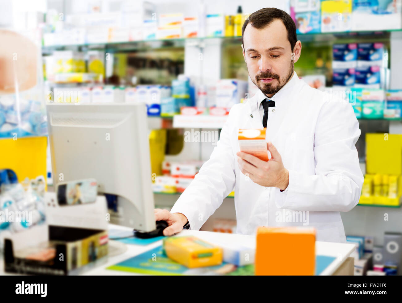 Positive male pharmacist checking assortment of drugs in pharmacy Stock ...