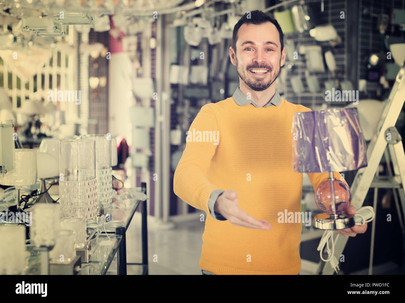 Male in lighter shop is choosing stylish and modern lamp for house ...