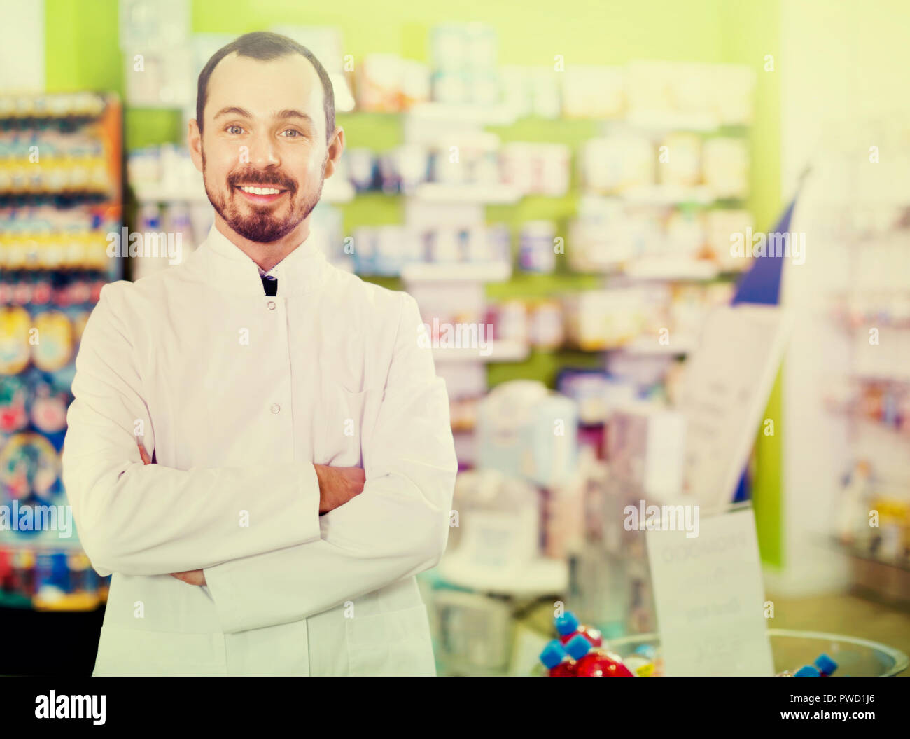 Smiling cheerful male pharmacist demonstrating assortment of drugs in ...