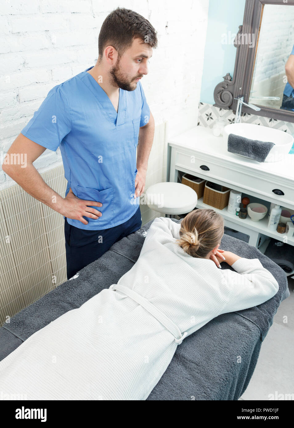 Professional massagist performing back massage to female client in spa ...