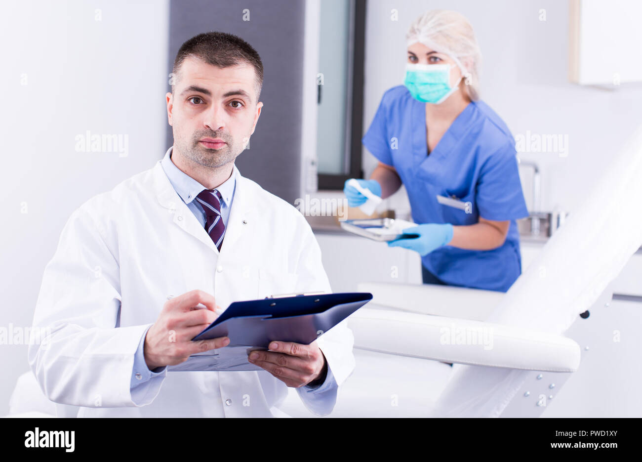 Confident doctor cosmetologist working with documents in modern ...