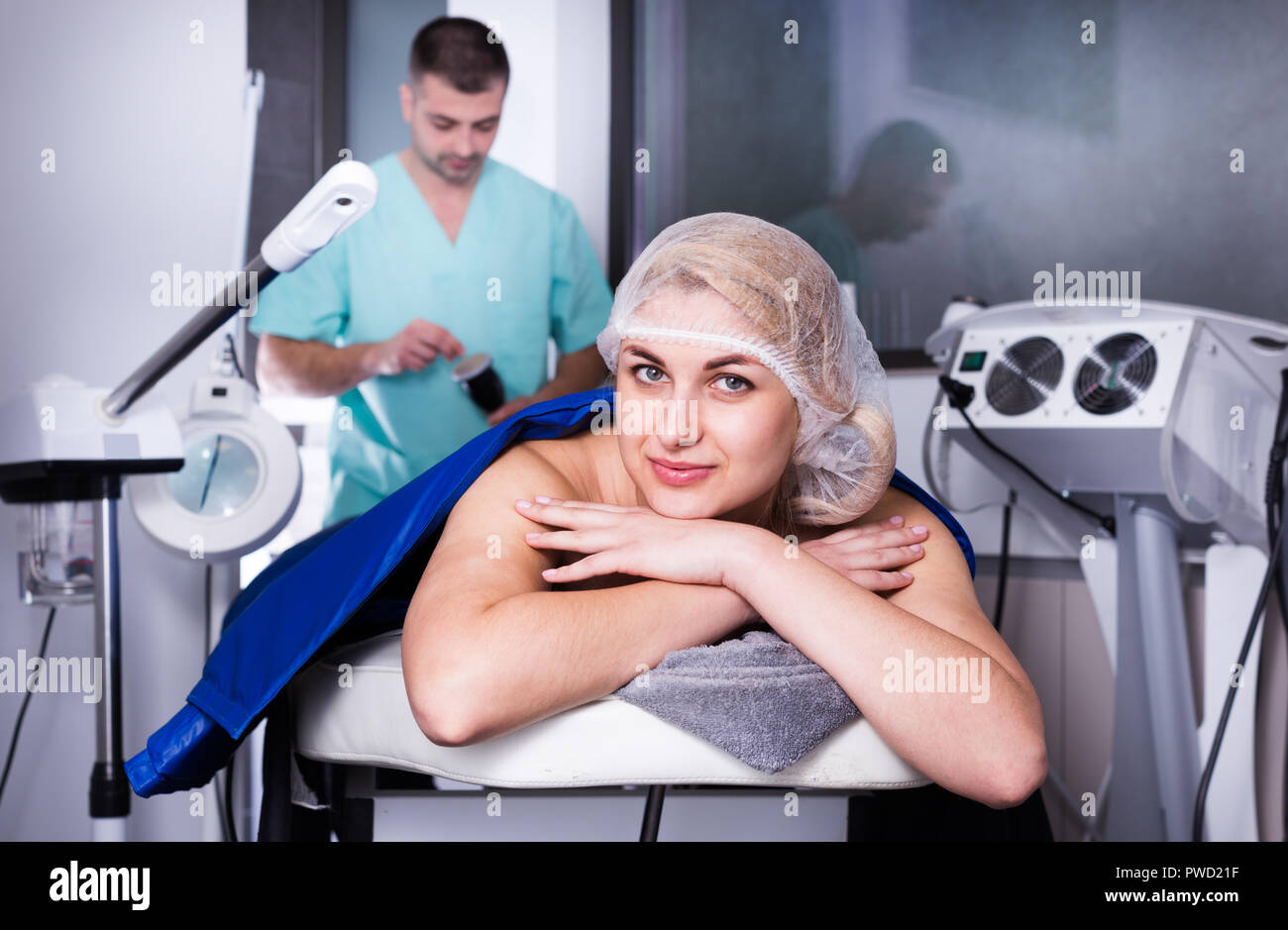 Portrait of young female during body procedure on modern equipment in ...