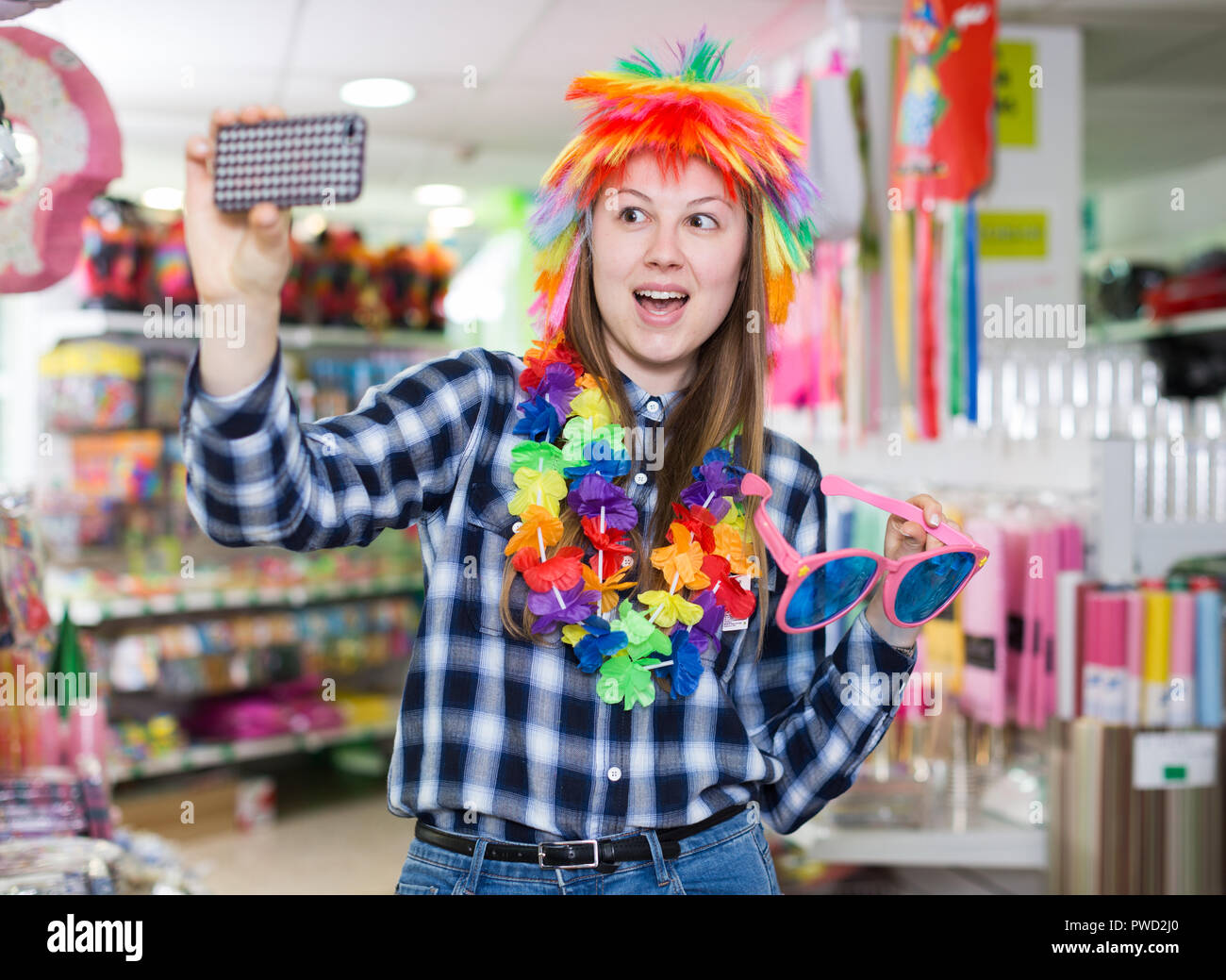 Cheerful young female taking selfie in festive things store while ...