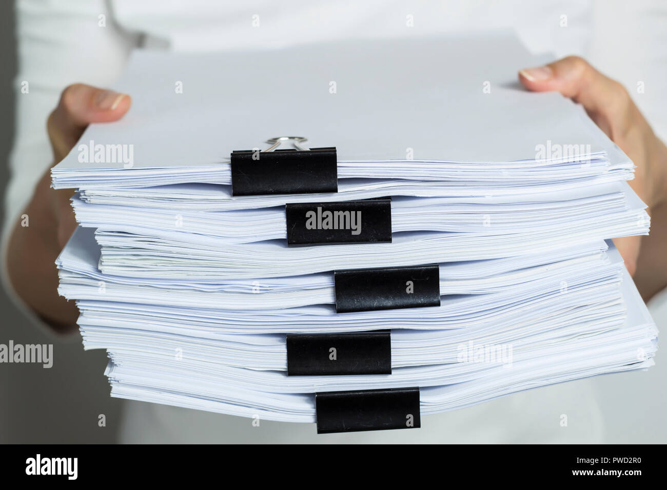 Hands touching office paper. Stacks documents files with black clip ...