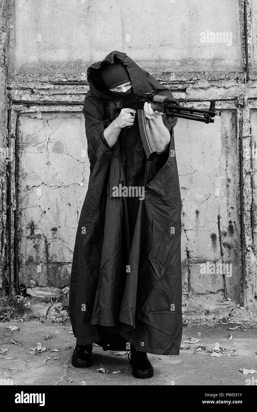 a man in a military coat and a balaclava aiming with Kalashnikov RPK ...