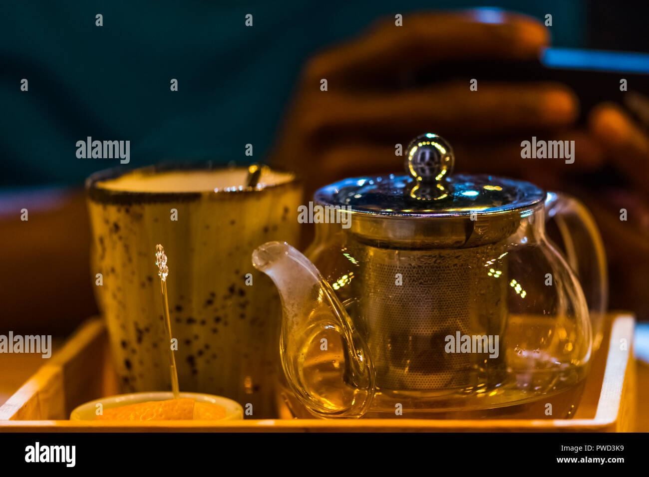 The cup of the tea and teapot in the wooden plate in front of the guy ...