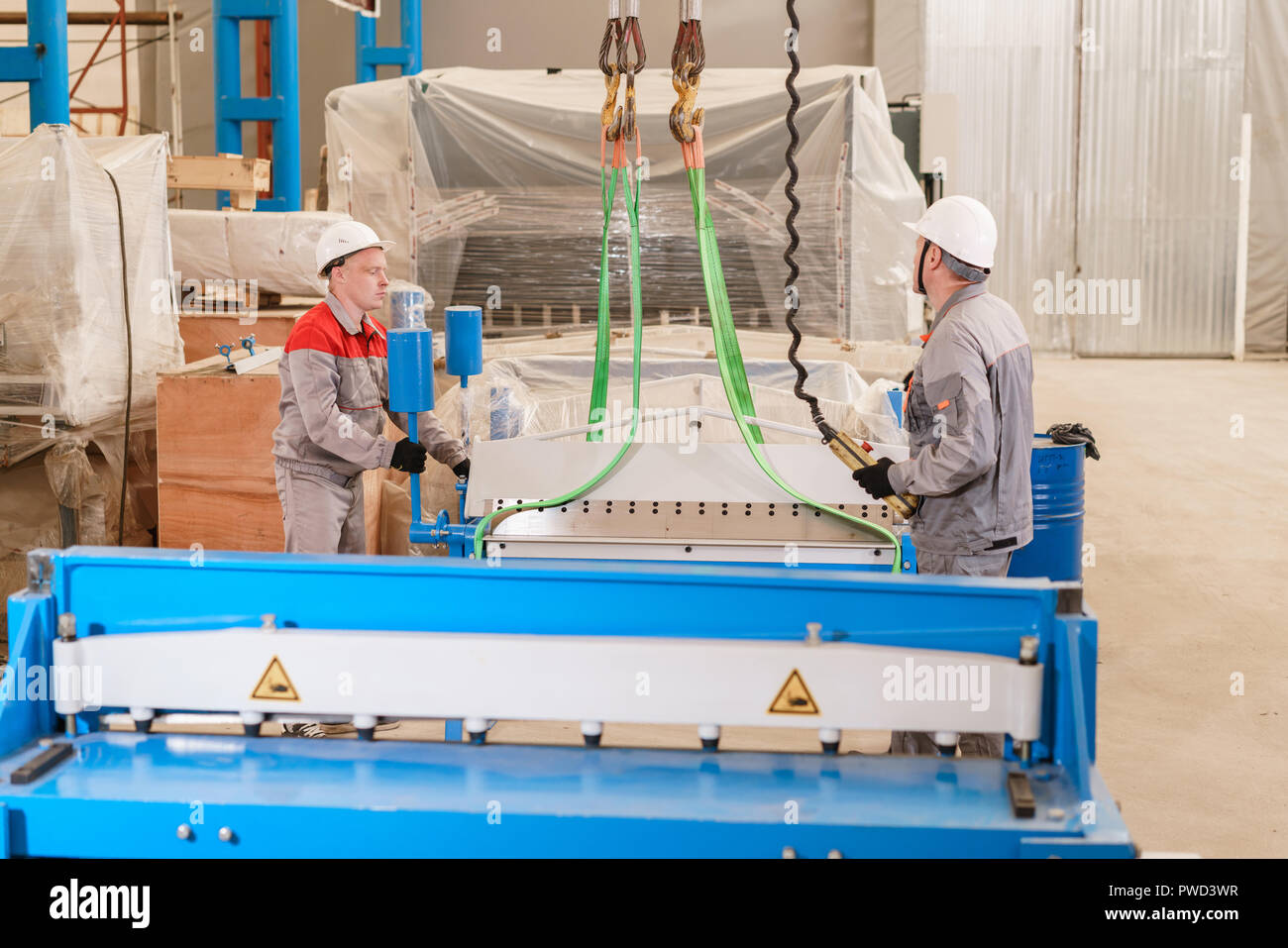 move the crane with beam. Workers adjusts the machine in the warehouse ...