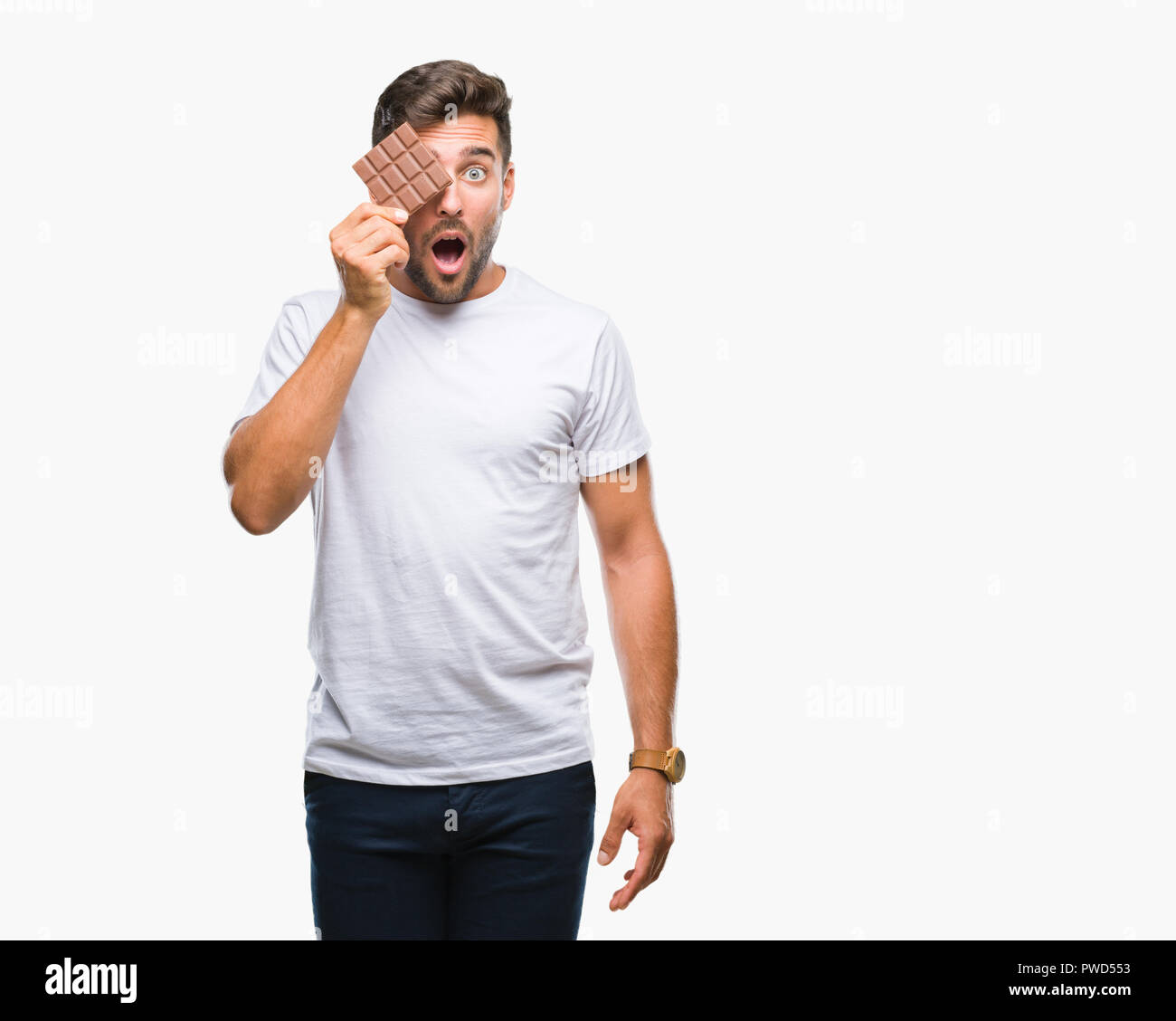 Young handsome man eating chocolate bar over isolated background scared ...