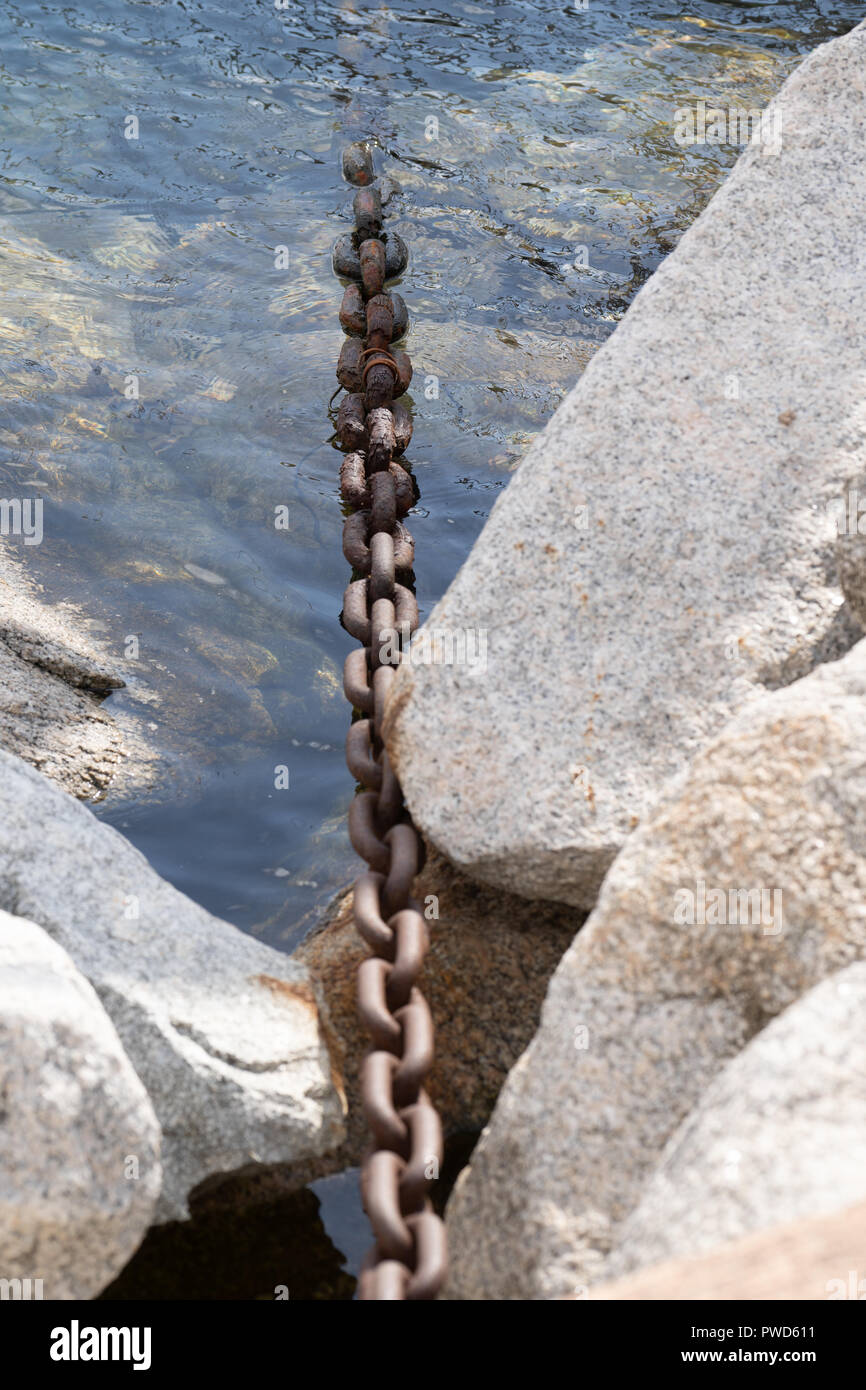 Photography of A Chain in the water and a stone on the left and on the ...
