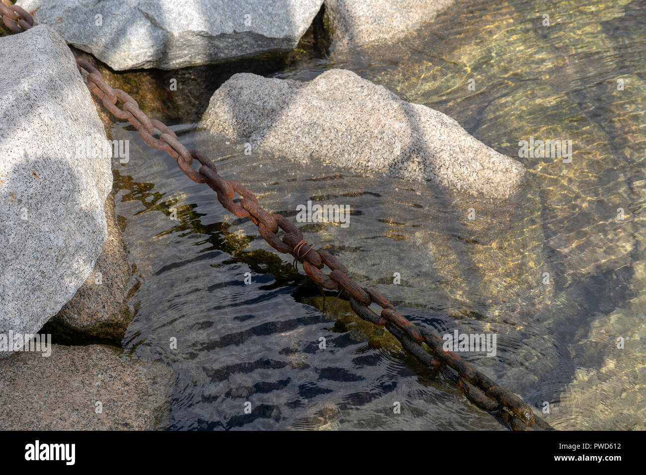 Photography of A Chain in the water and a stone on the left and on the ...