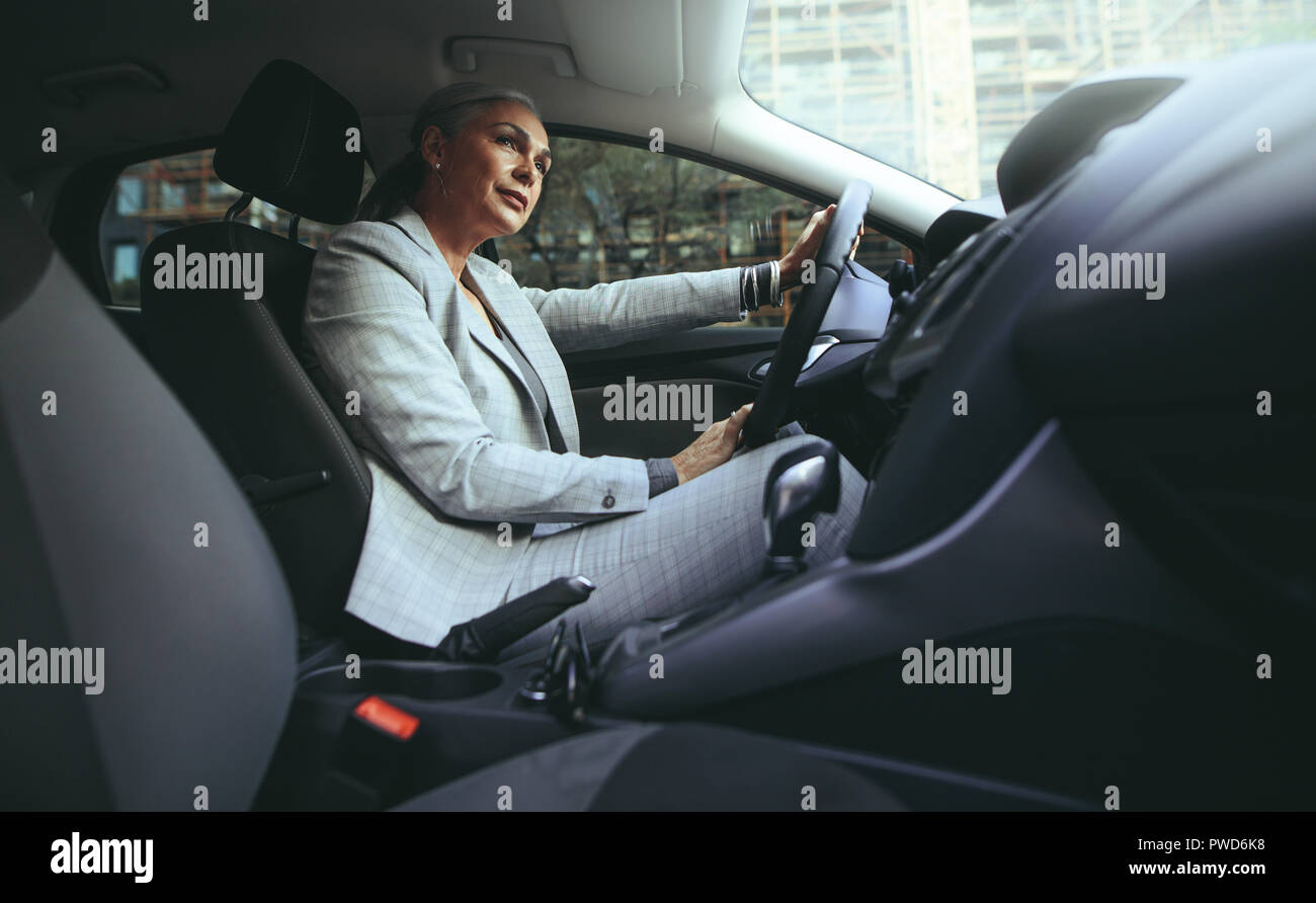 Mature woman driving a car. Senior female driver at a wheel of a modern ...
