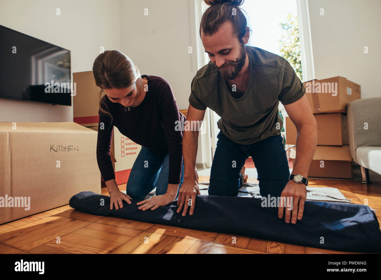Smiling man and woman packing their household items in packing boxes ...