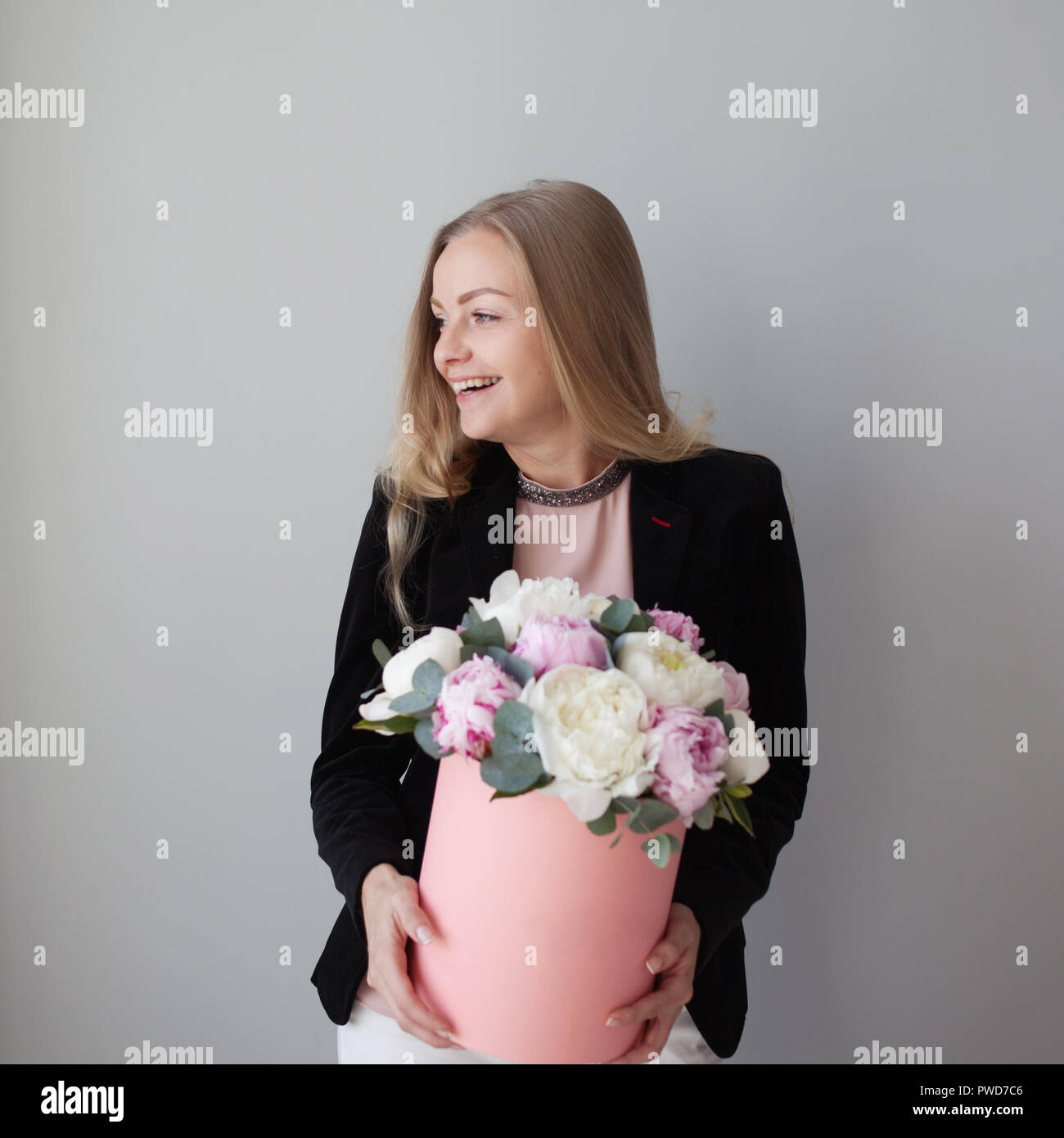 Charming blonde woman with flowers in a hat box. Bouquet of peonies ...