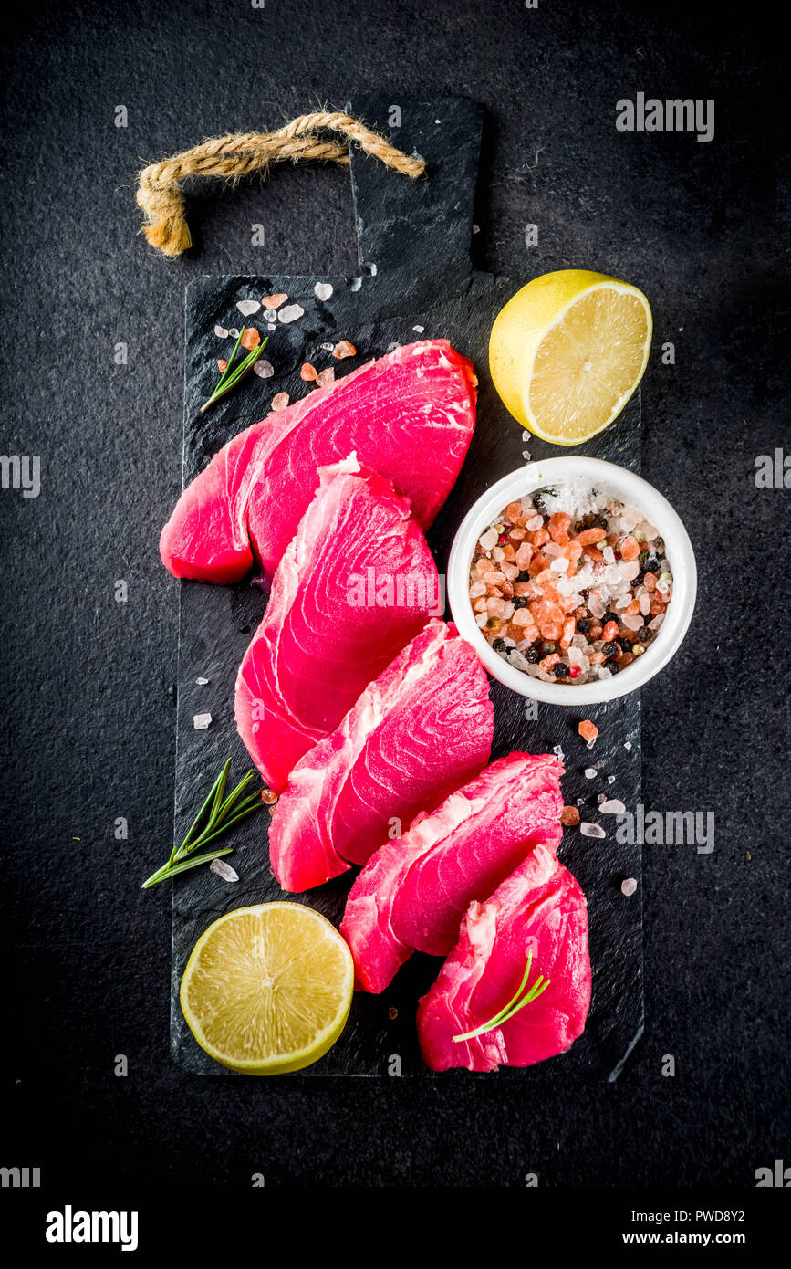 Fresh raw tuna fish steaks with ingredients for cooking, black stone ...