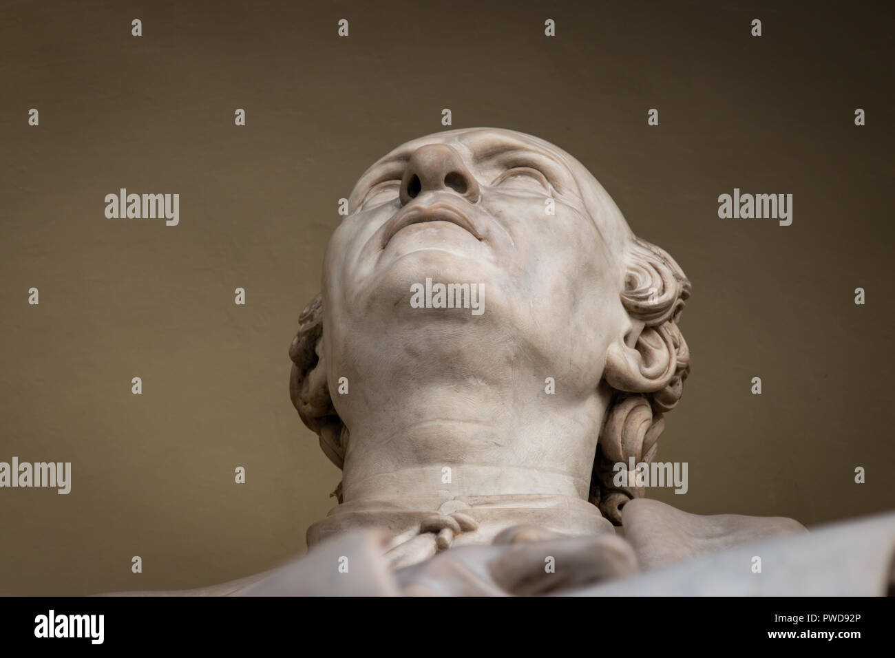 A closeup of the top of a marble statue, showing a man's head looking ...