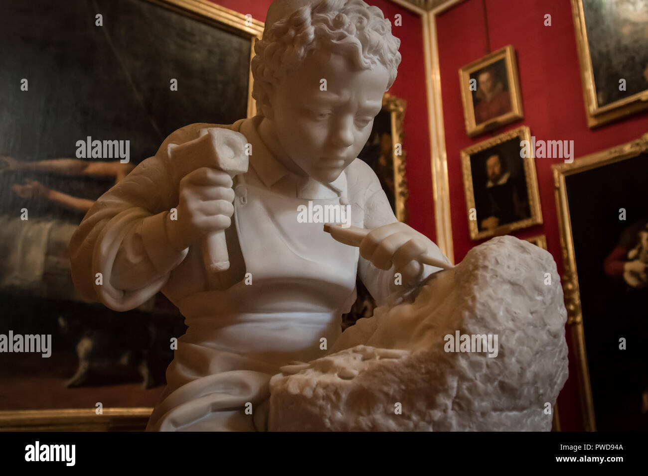 A young workman wields hammer and chisel on a block of marble in this ...