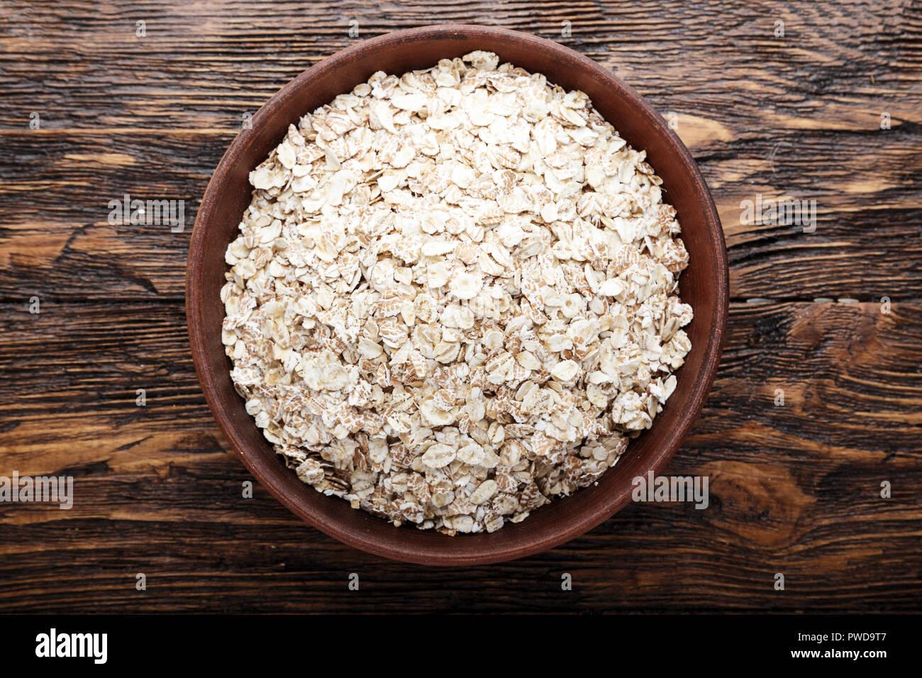 raw oatmeal in a clay plate close-up. cooking breakfast oatmeal. place ...