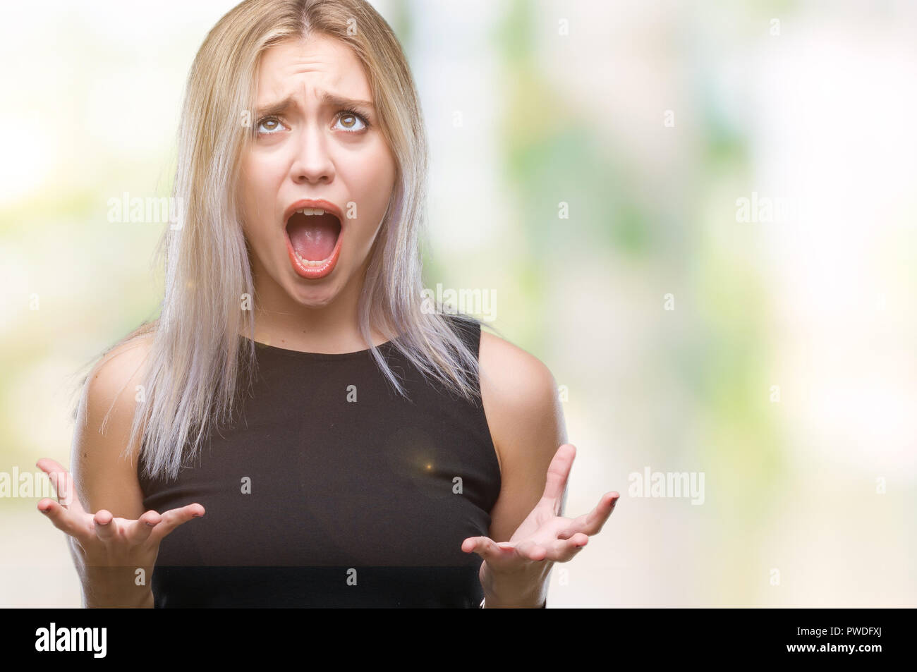 Young blonde woman over isolated background crazy and mad shouting and ...