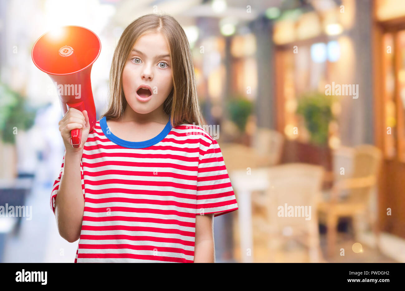 Young beautiful girl yelling through megaphone over isolated background ...