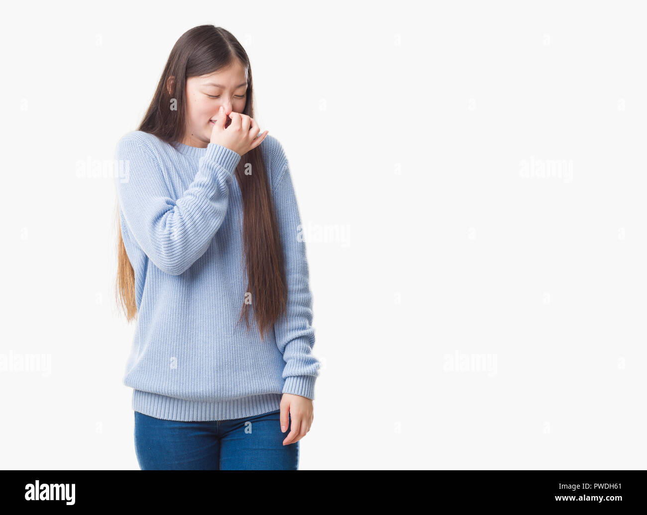 Young Chinese woman over isolated background smelling something stinky ...