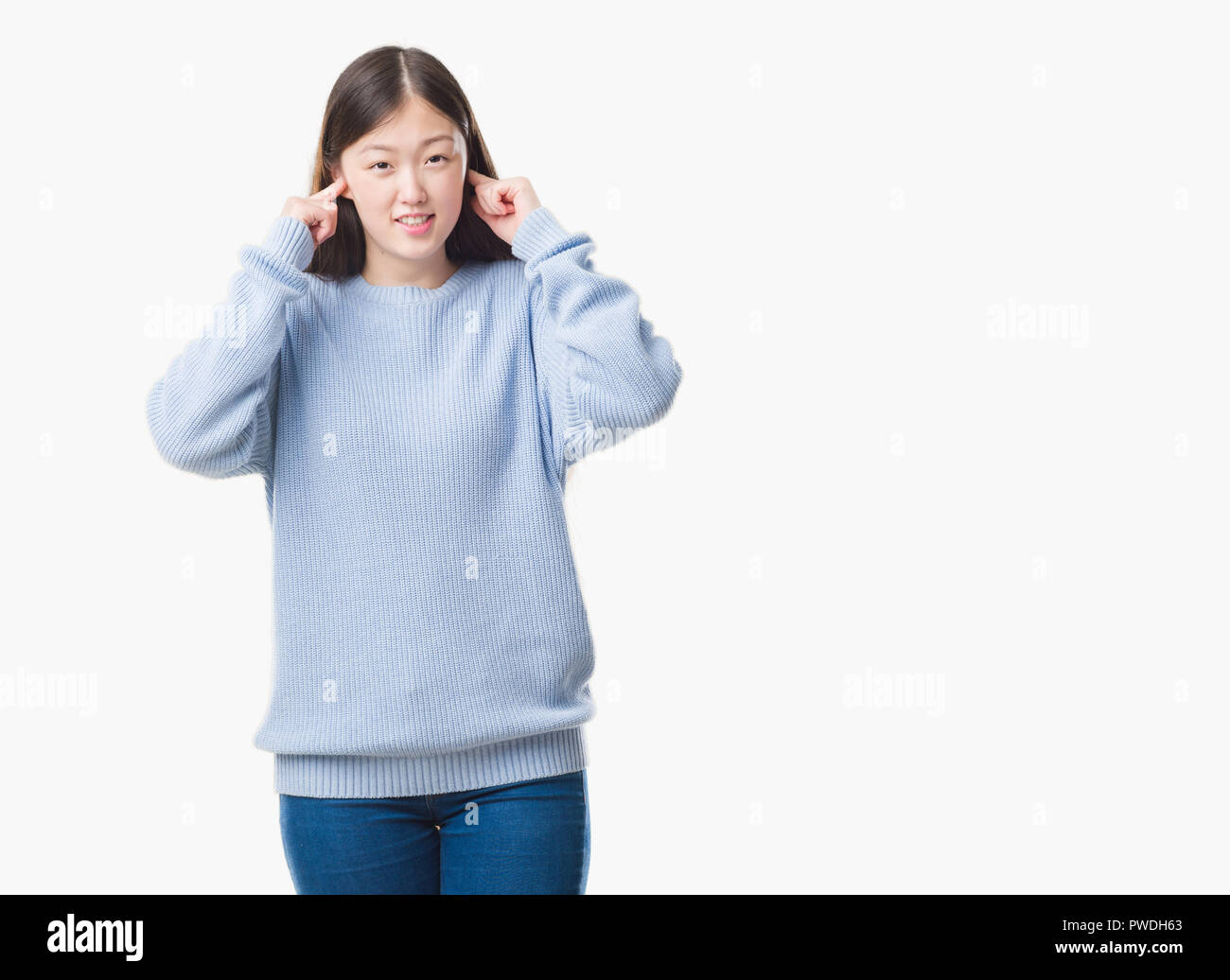Young Chinese woman over isolated background covering ears with fingers ...