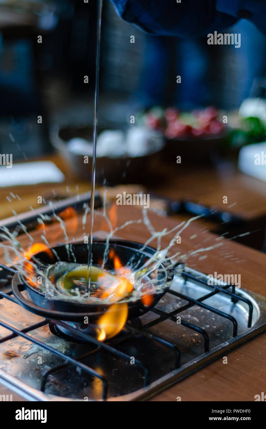 Chef is cracking egg to the frying pan while of spilling to the air ...
