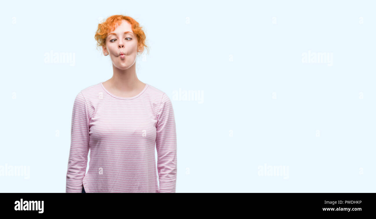 Young redhead woman making fish face with lips, crazy and comical ...