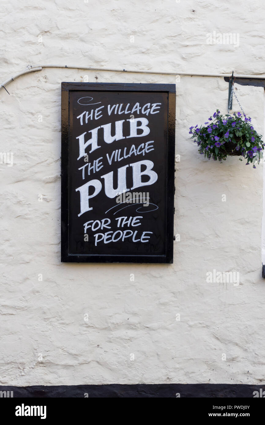 Sign on the whitewashed wall of a village pub stating "The Village Pub ...