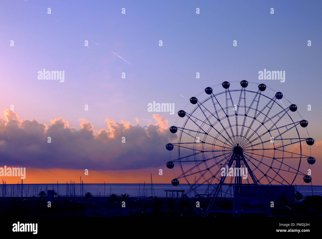 Ferris wheel silhouette, ocean with fishing boats in the background ...