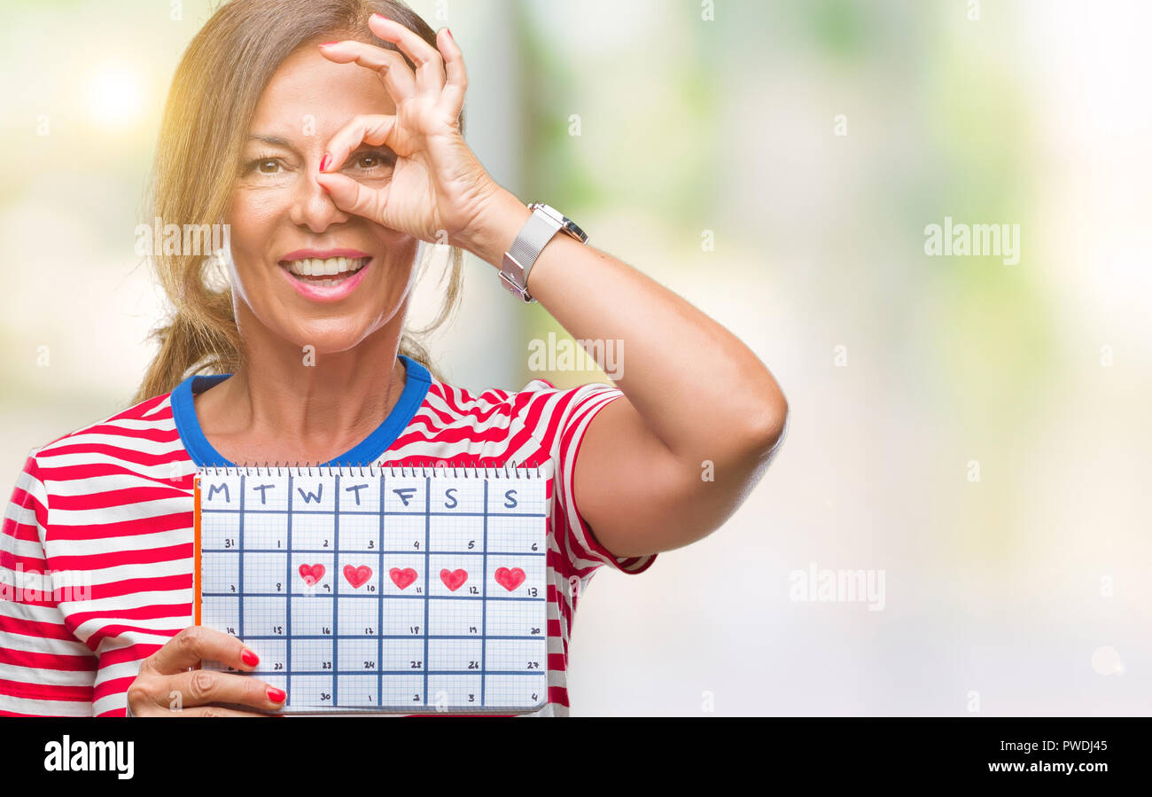 Middle age senior hispanic woman holding menstruation calendar over ...