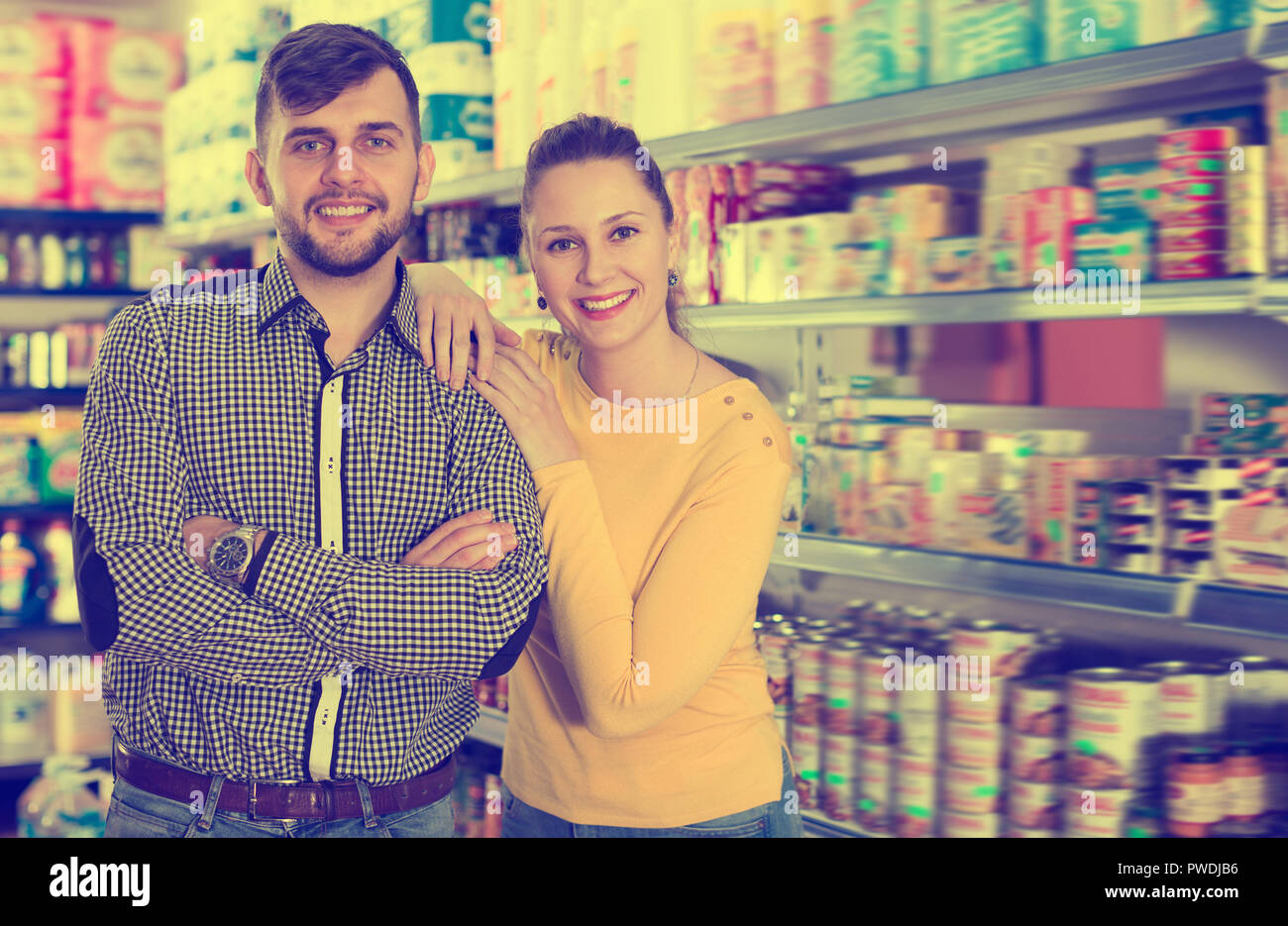 Young loving couple standing among shelves with groceries in ...
