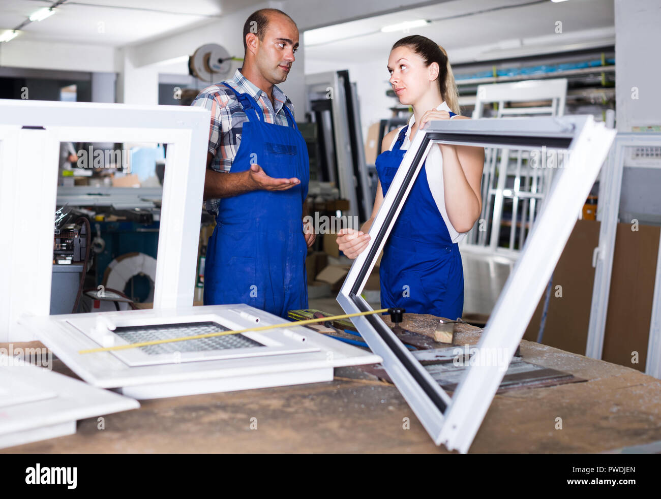 smiling foreman explaining plastic windows assembly process to young ...
