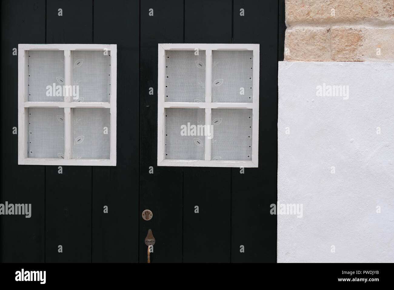 Square white windows with lace curtains in green wooden doors ...
