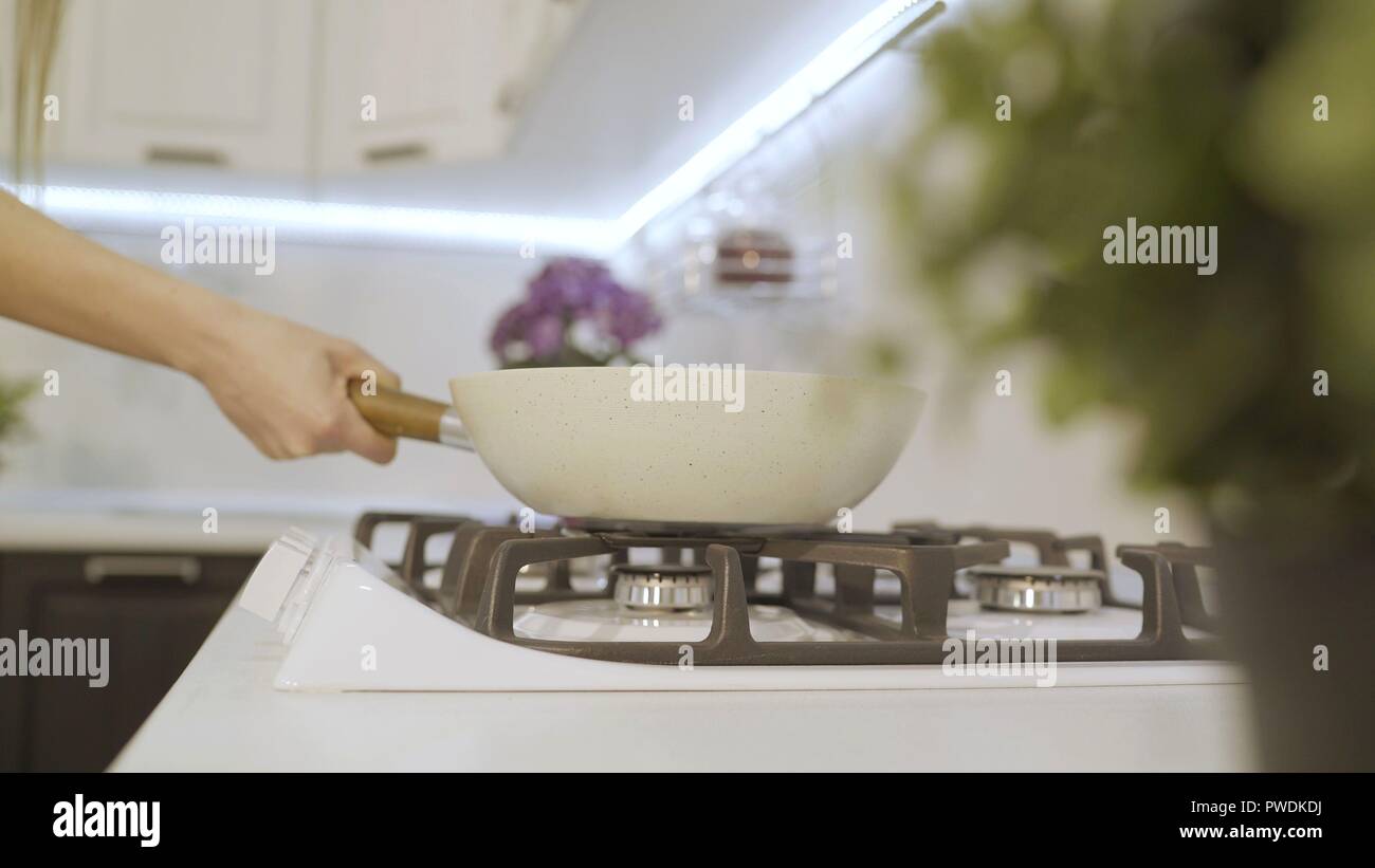Female hand puts a white frying pan on the gas stove Stock Photo - Alamy