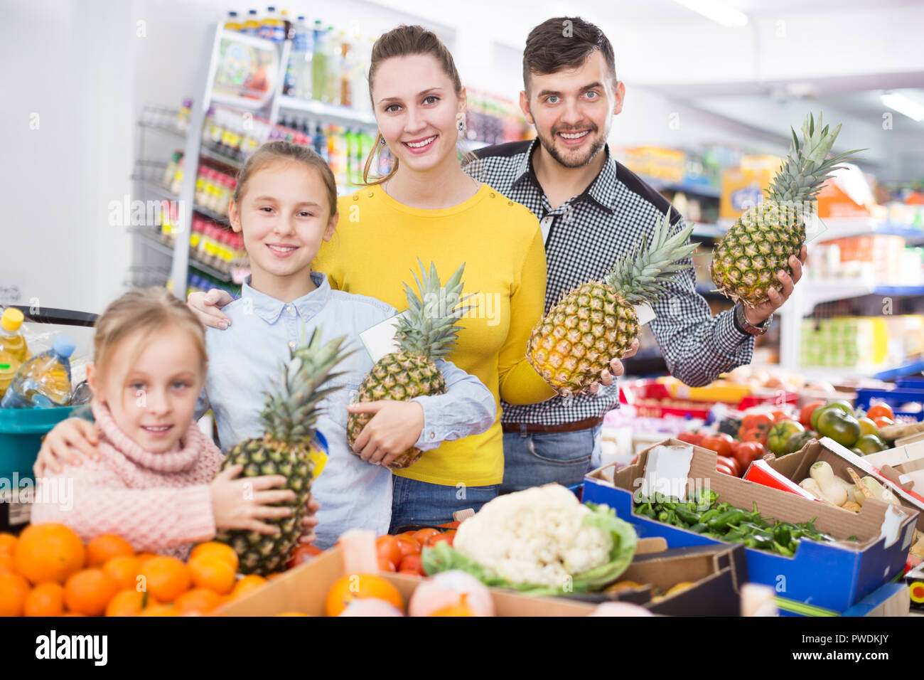 Friendly family of four with fruits and vegetables in greengrocery ...