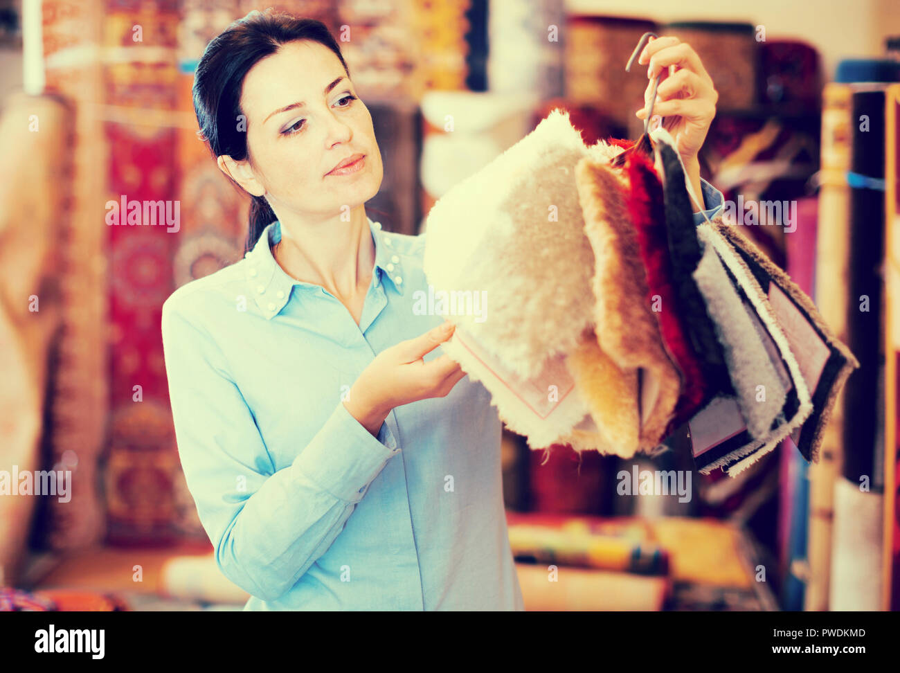 Adult woman shopping carpet and showing samples in interior store Stock ...