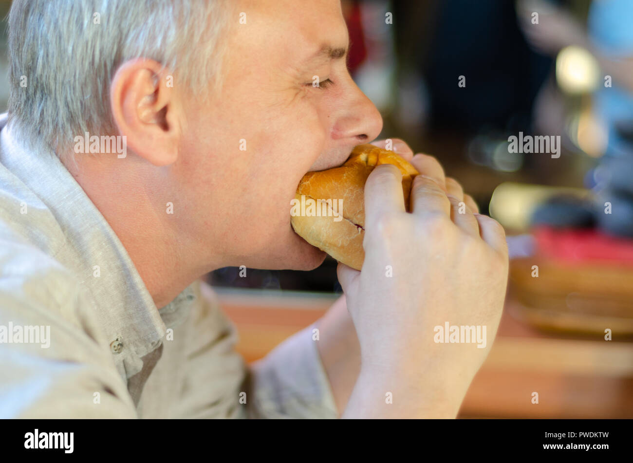 The Man with pleasure bites an appetizing burger in a steak house ...