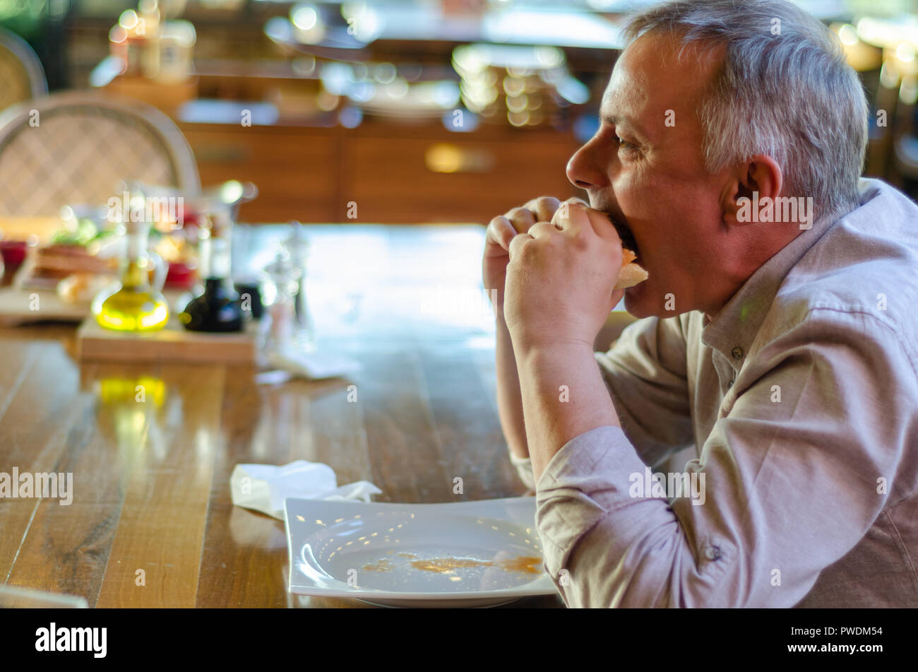 The Man with pleasure bites an appetizing burger in a steak house ...