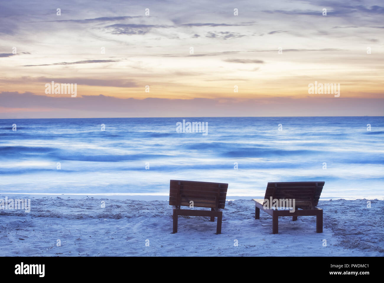 Moody sunset beach with two sunbeds. long exposure Stock Photo - Alamy