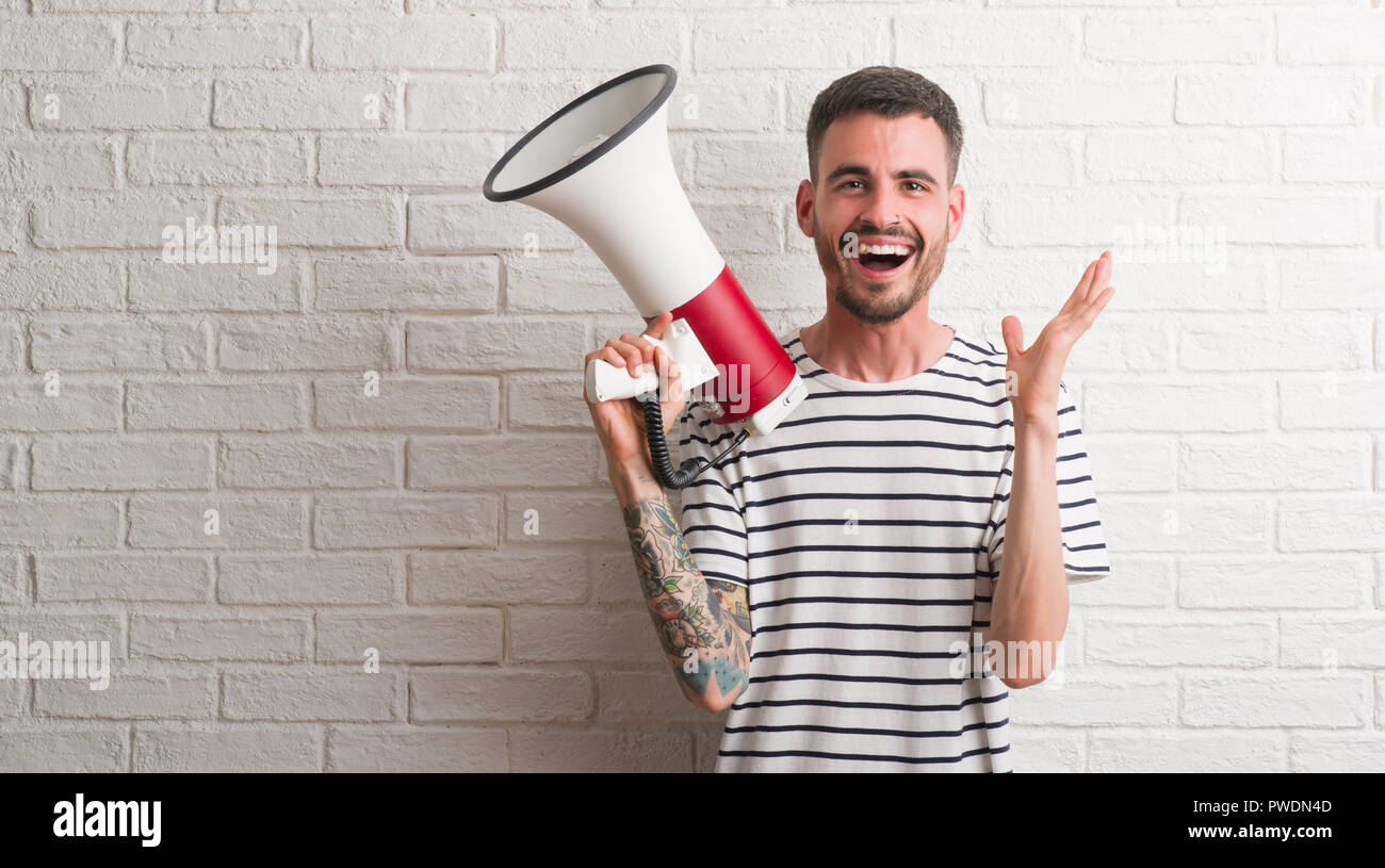Young adult man holding megaphone very happy and excited, winner ...