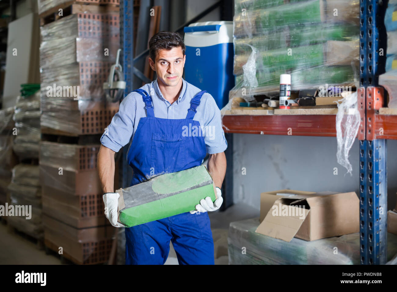 attractive male in uniform is choosing cement in the building store ...